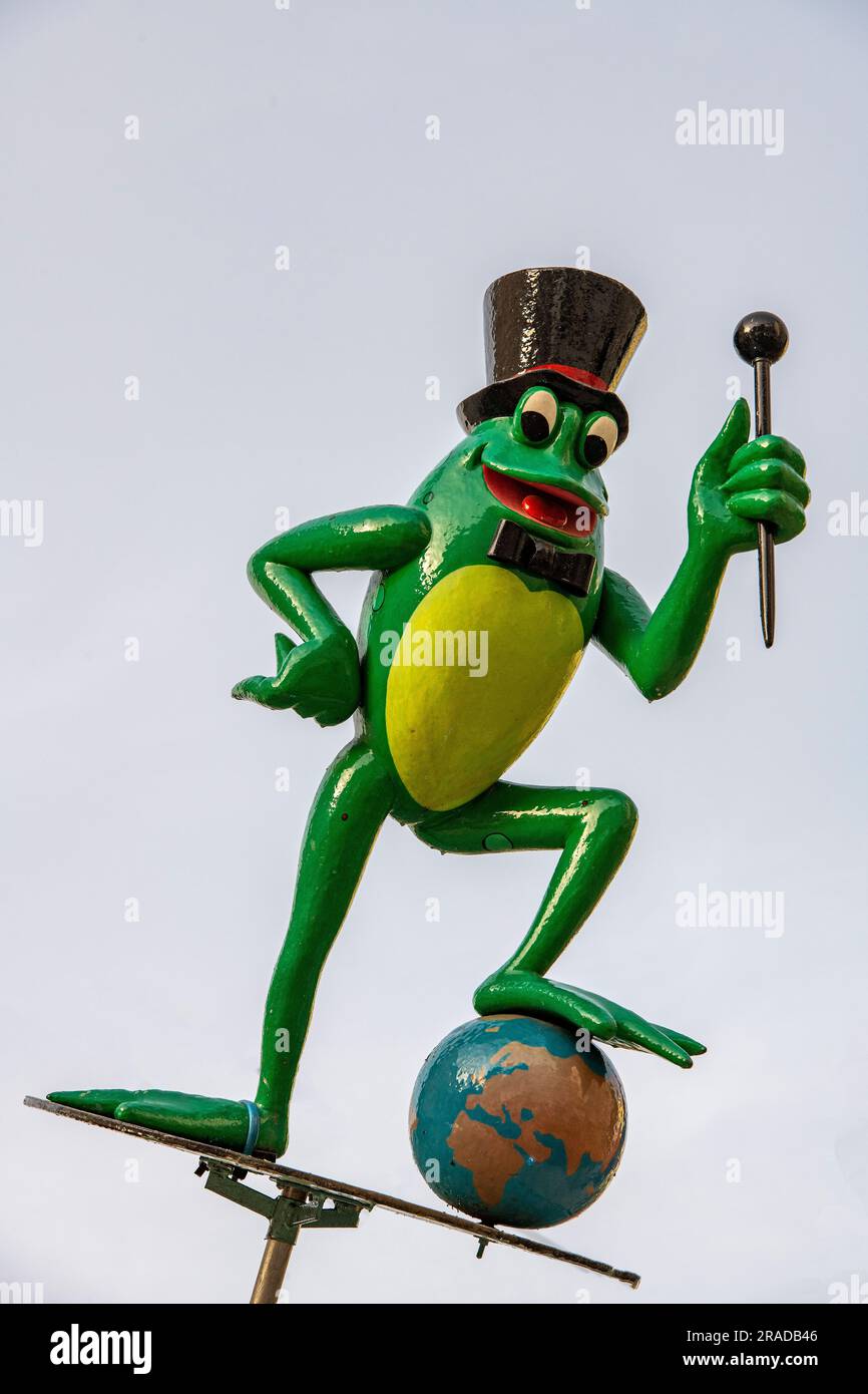 large green plastic frog wearing a top hat and holding a baton at the ...
