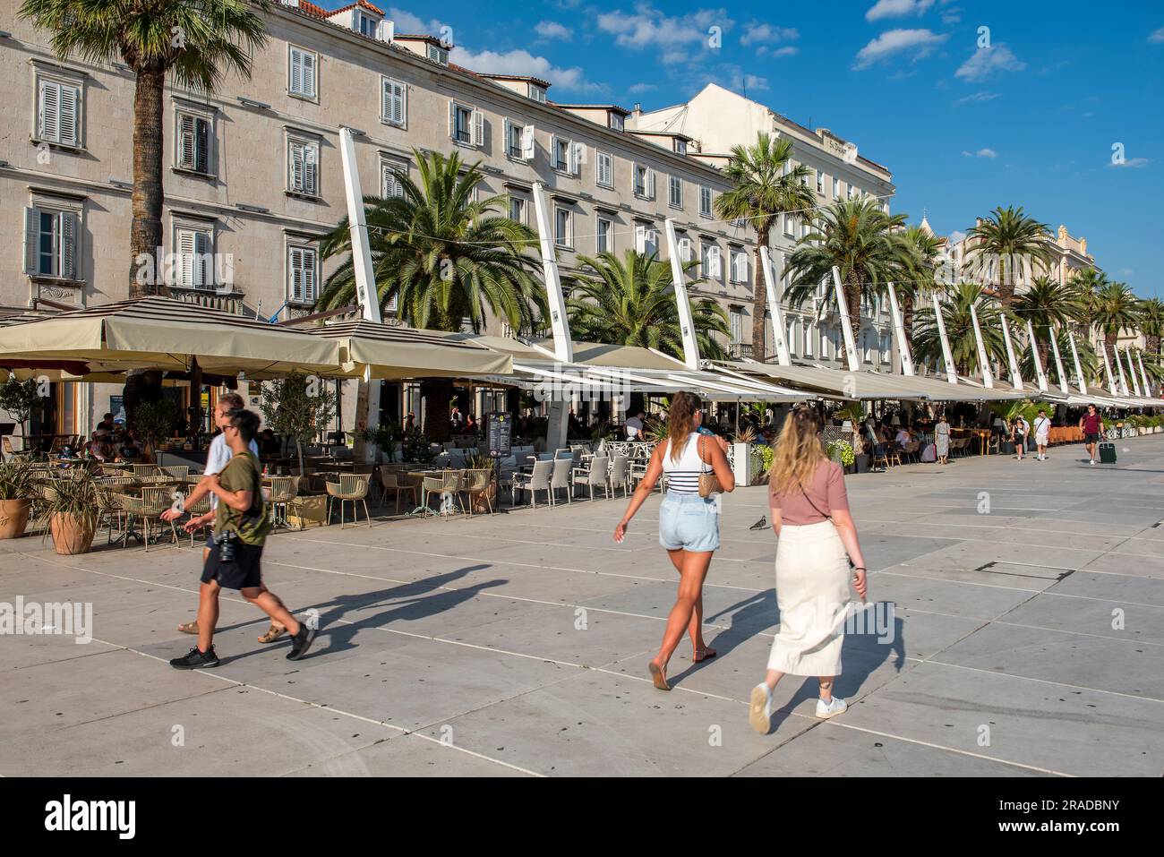 tourists walking along the waterfront paved area with restaurants and ...