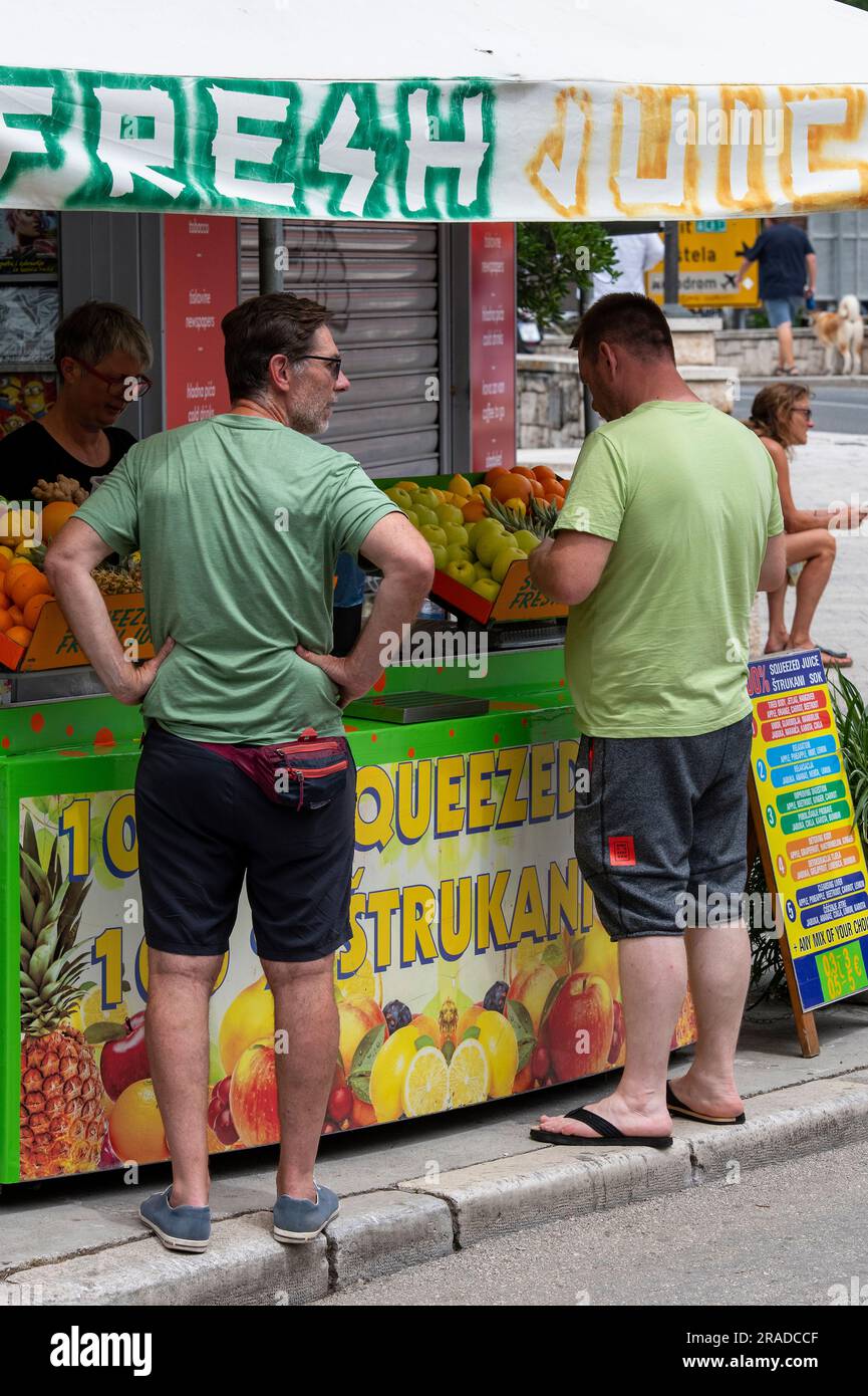 twom men standing at a fresh fruit juice counter in trogir, croatiam ...