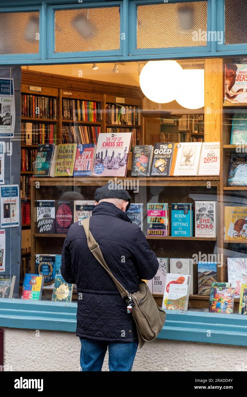 older man looking into bookshop window, elderly man window shopping at ...
