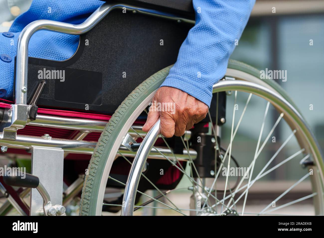 close up hand of disabled senior woman on the wheel of a wheelchair ...