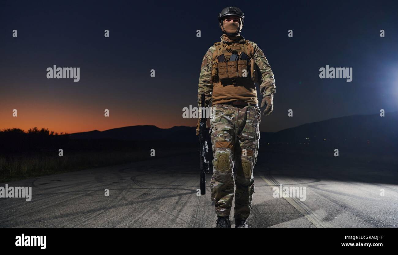A professional soldier in full military gear striding through the dark ...