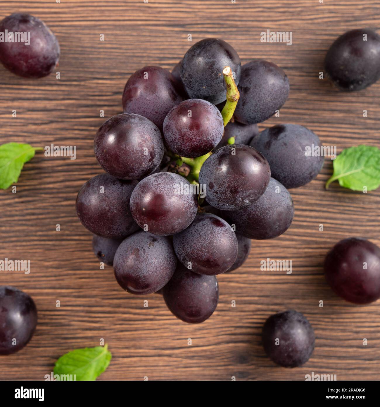 Delicious bunch of purple grapes fruit spilled over wooden table ...