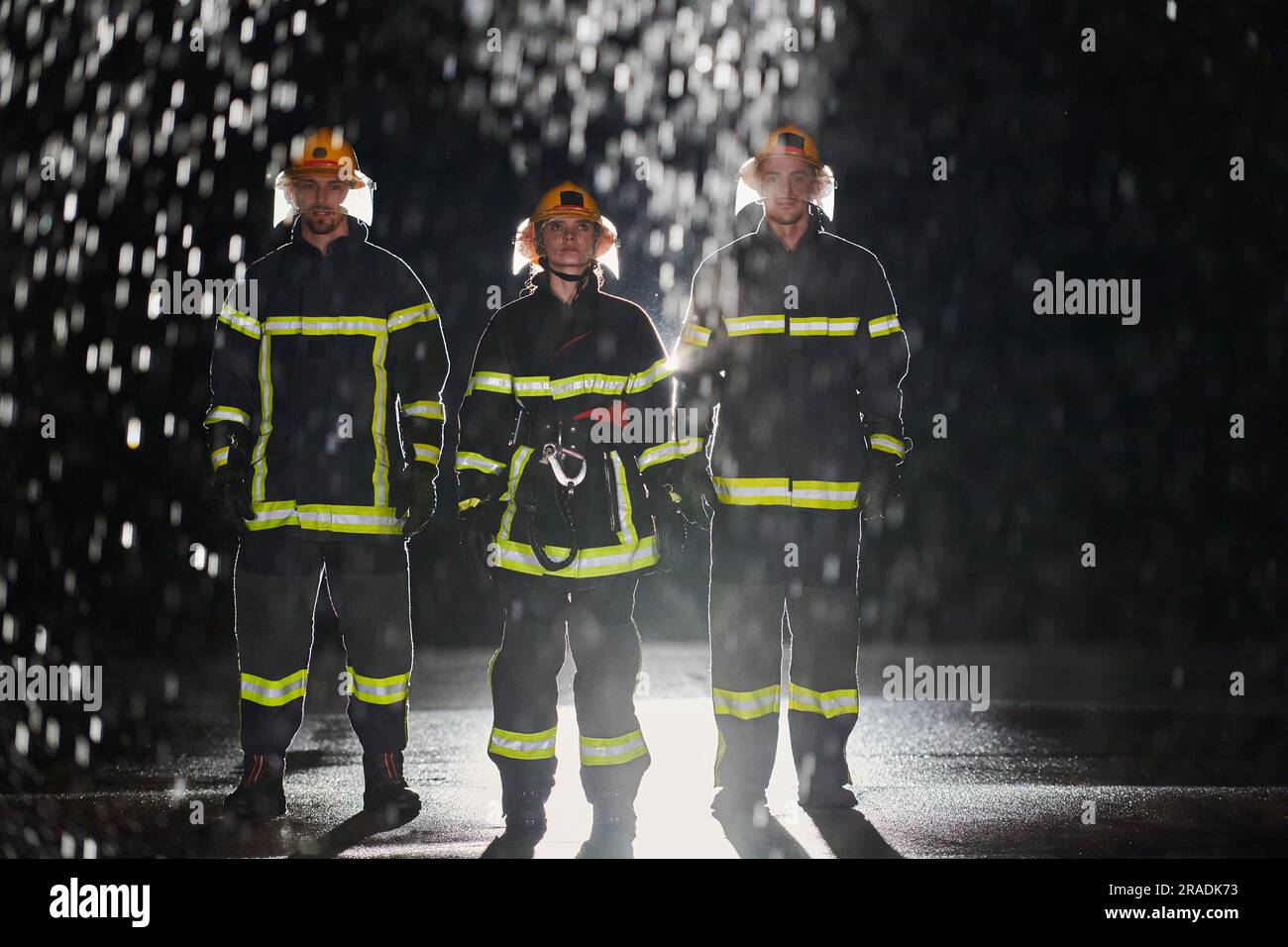A group of professional firefighters marching through the rainy night ...