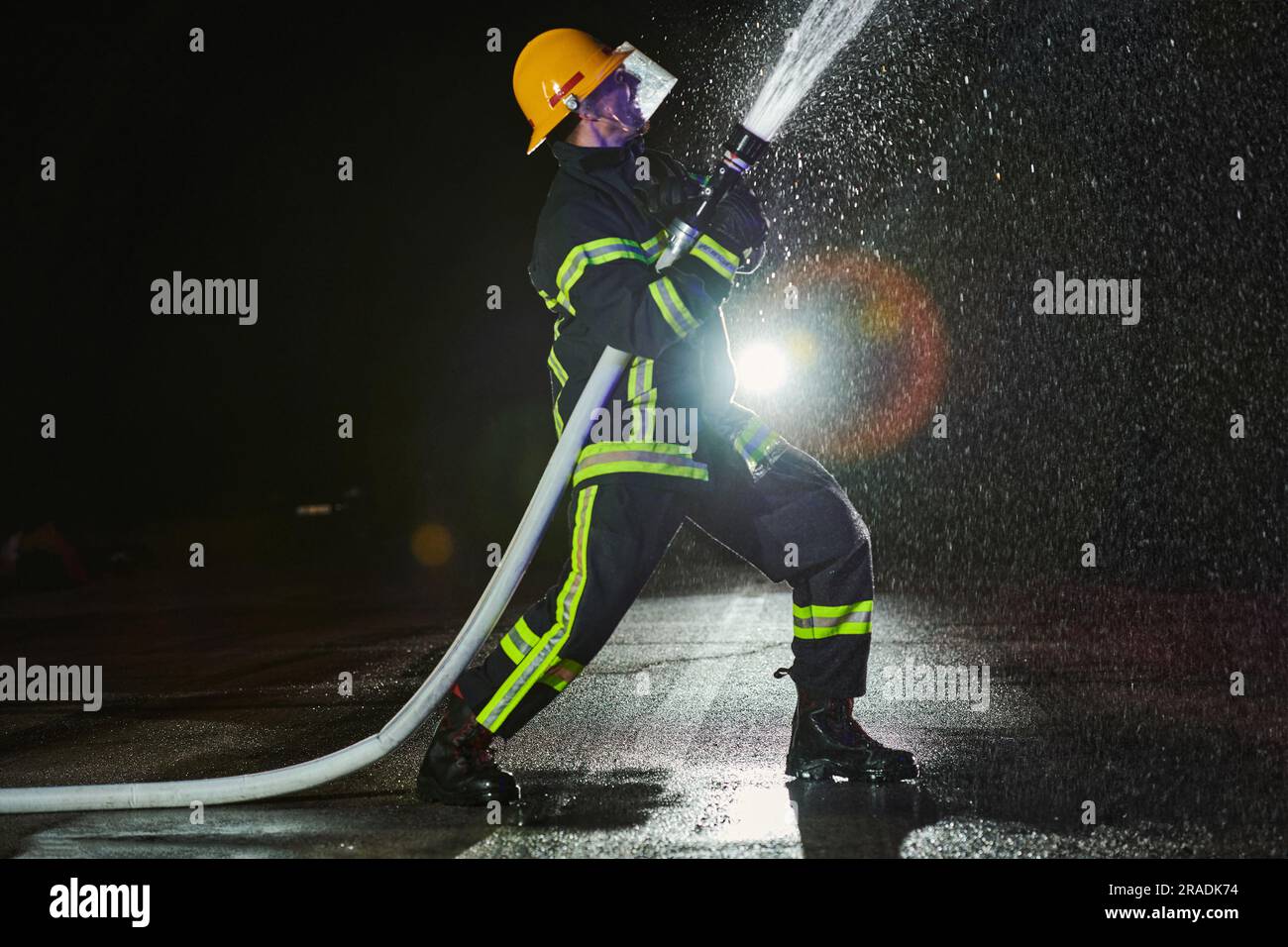 Firefighter using a water hose to eliminate a fire hazard. Team of ...