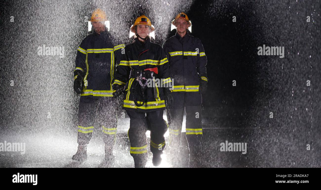 A group of professional firefighters marching through the rainy night ...
