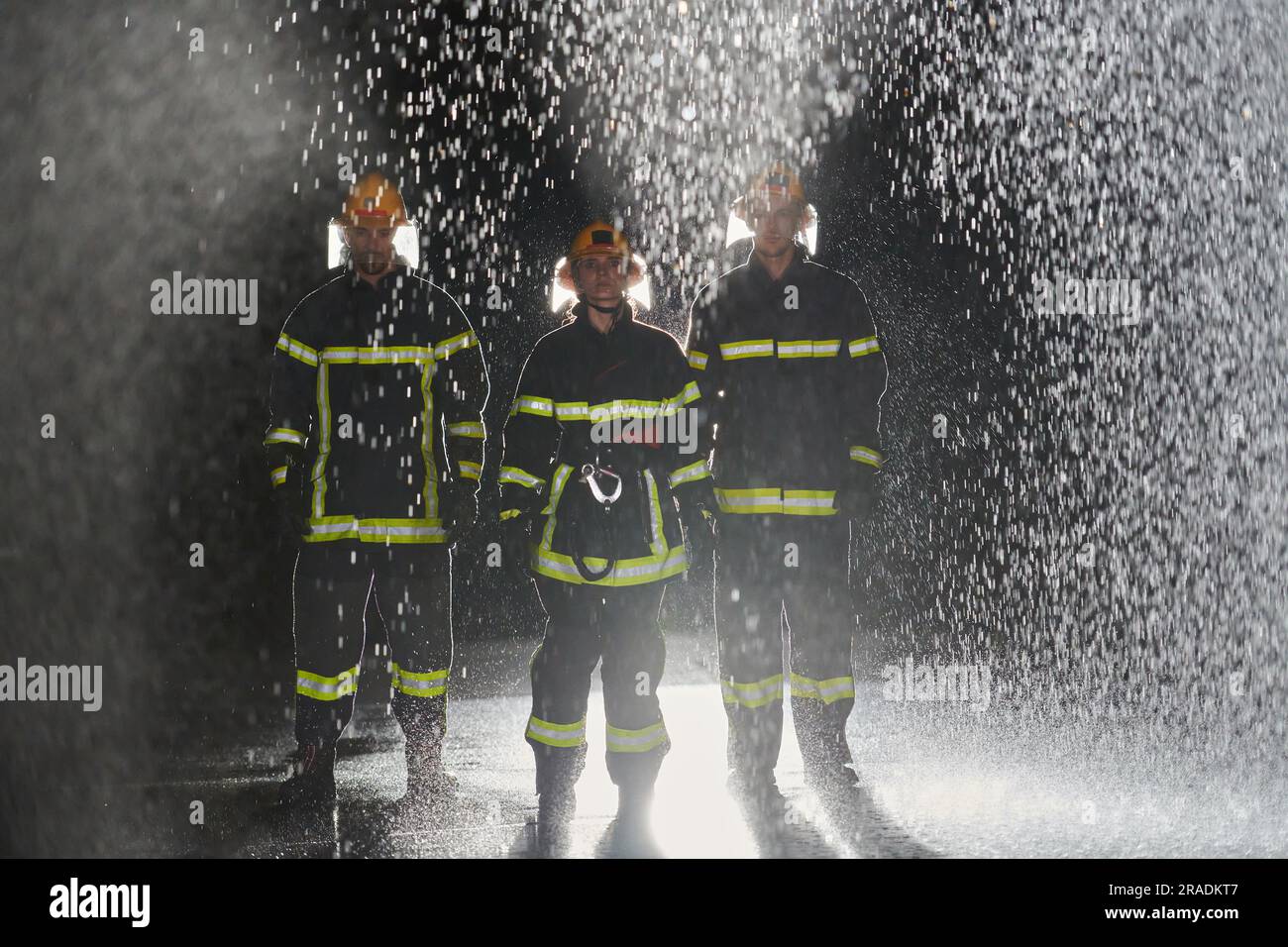 A group of professional firefighters marching through the rainy night ...