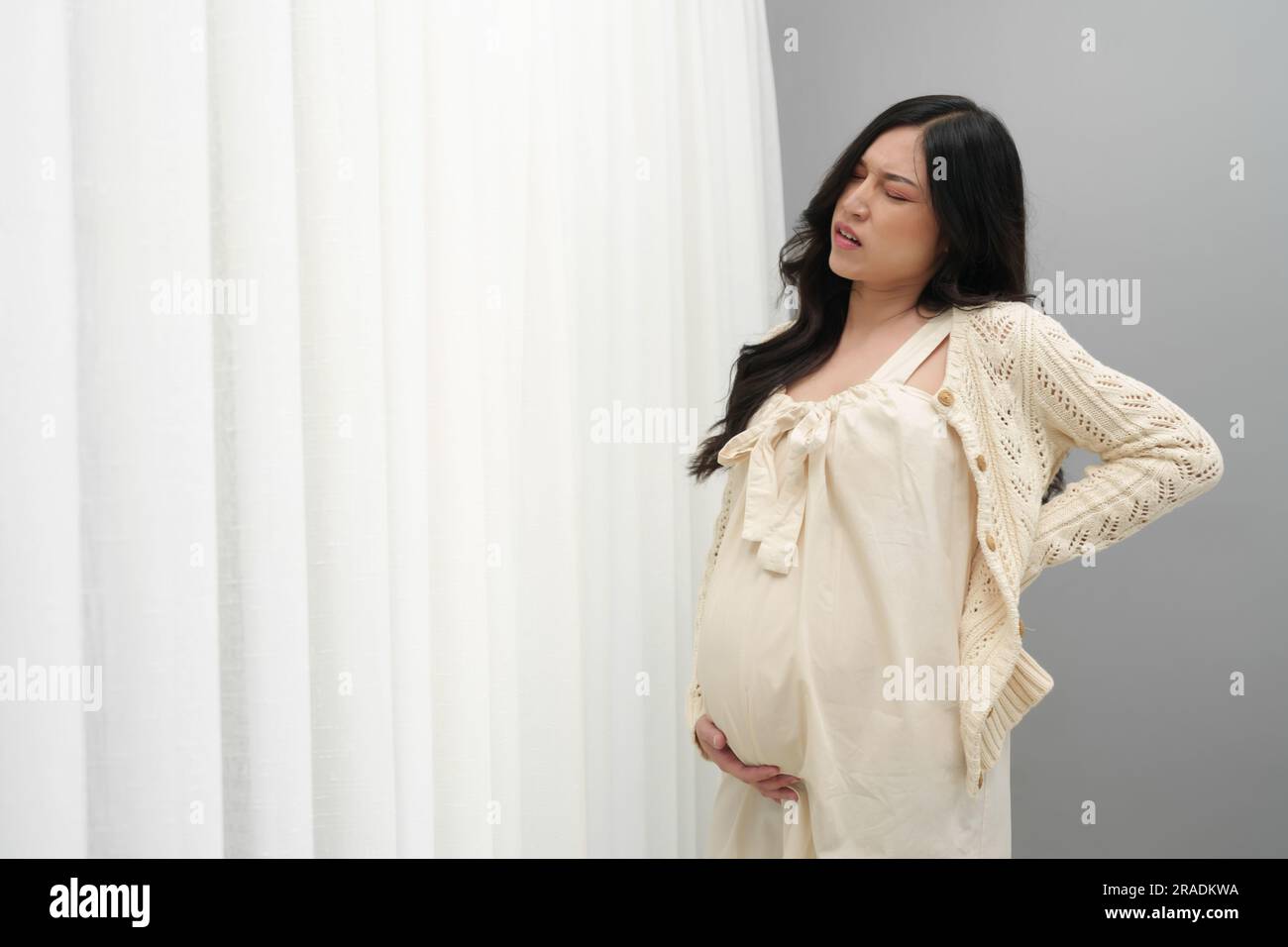pregnant woman suffering lower back pain near the window Stock Photo ...