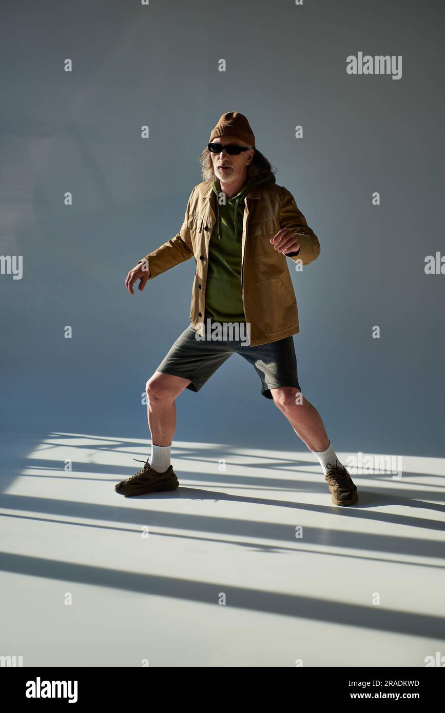 full length of expressive senior man in trendy hipster clothes and dark ...