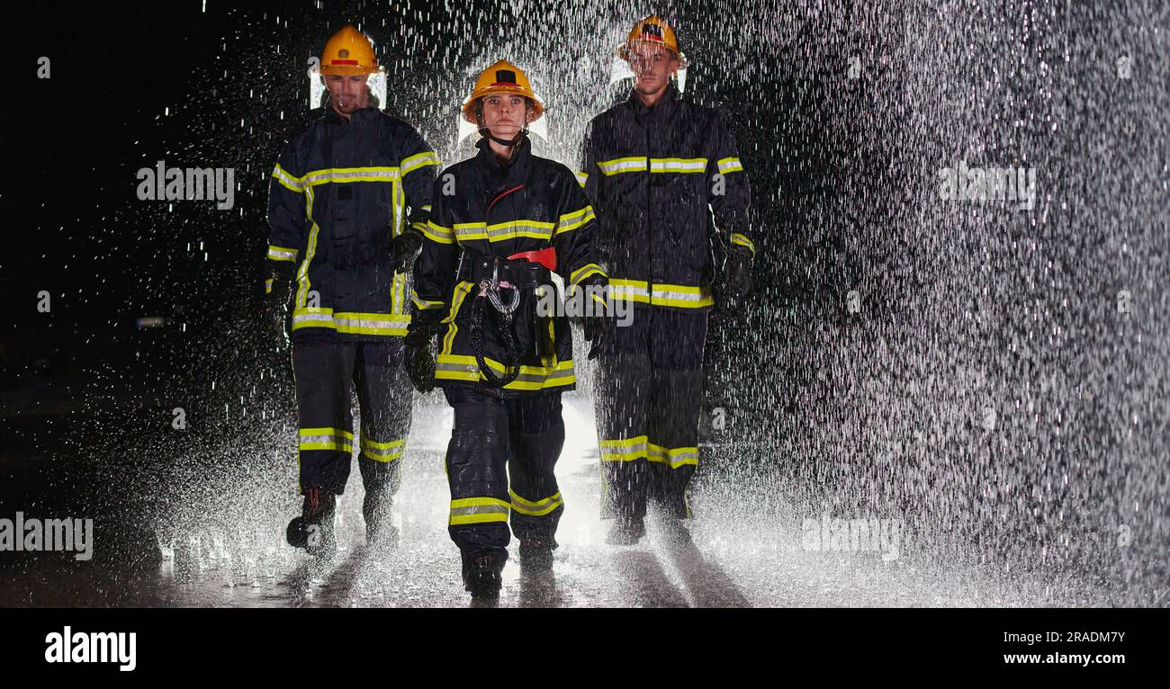 A group of professional firefighters marching through the rainy night ...