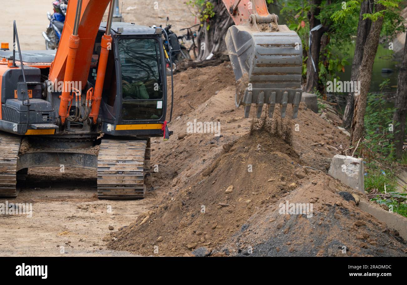 Digger working by digging soil at construction site. Bucket teeth of backhoe digging sand ...