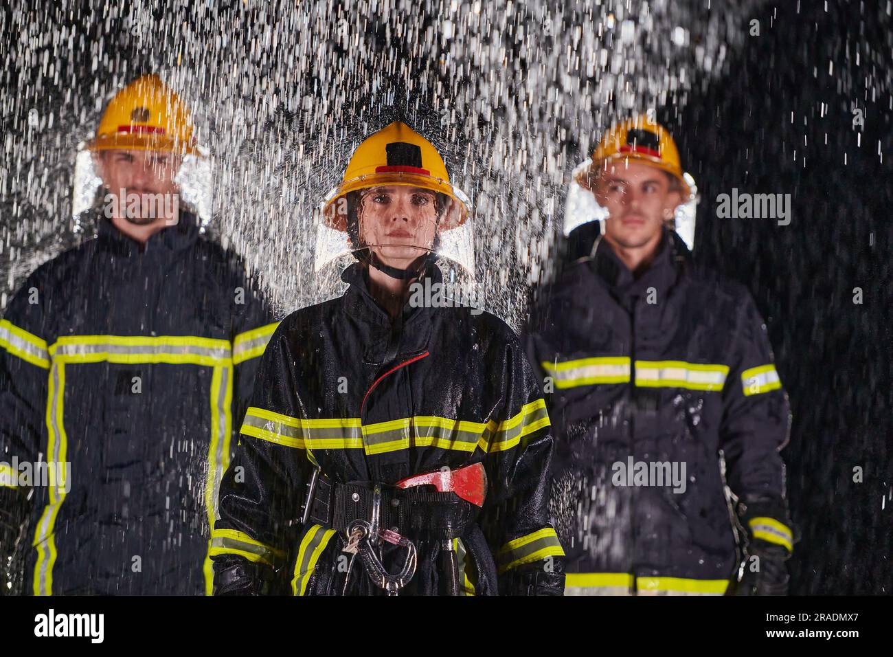 A group of professional firefighters marching through the rainy night ...