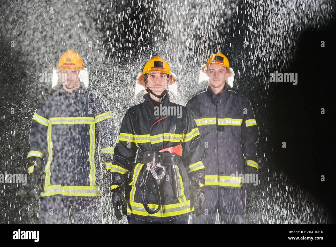 A group of professional firefighters marching through the rainy night ...