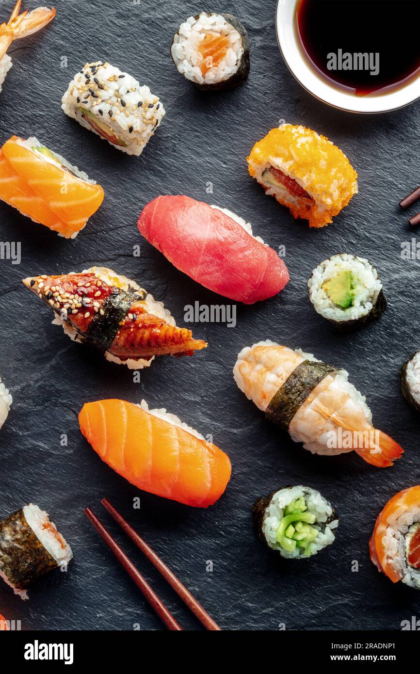 Sushi, shot from the top with chopsticks and soy sauce. Rolls, maki, nigiri on a black ...