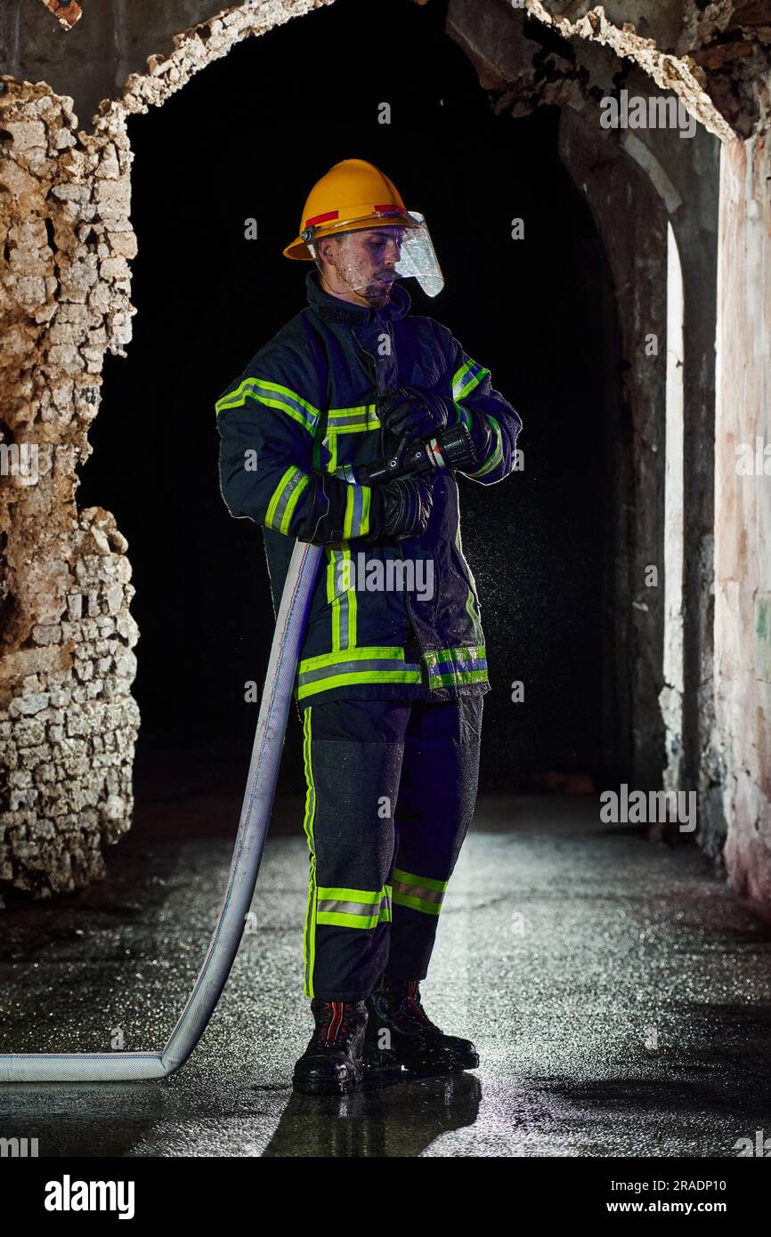 Firefighter using a water hose to eliminate a fire hazard. Team of ...