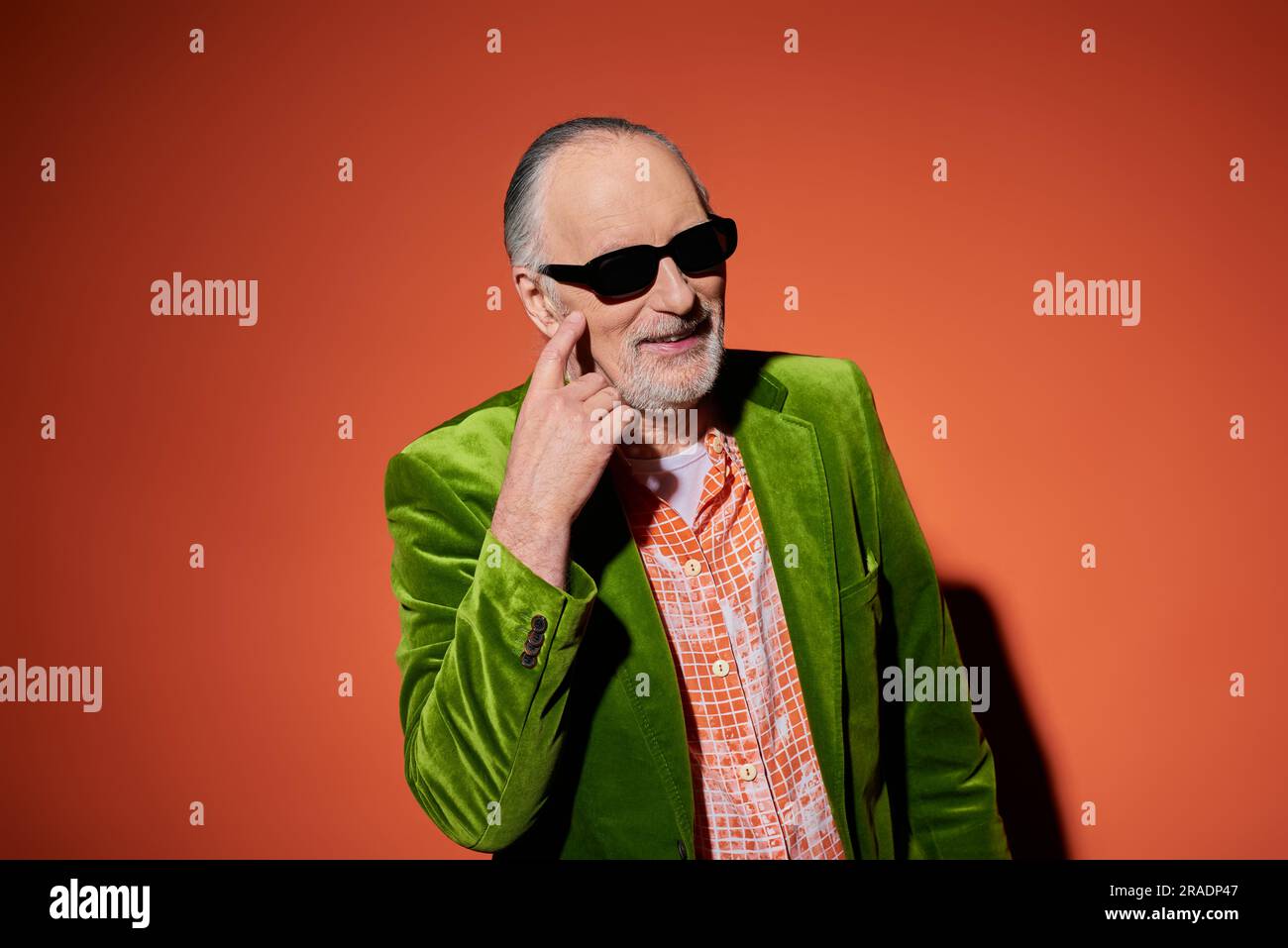 playful and fashionable senior man pointing at cheek while asking for ...