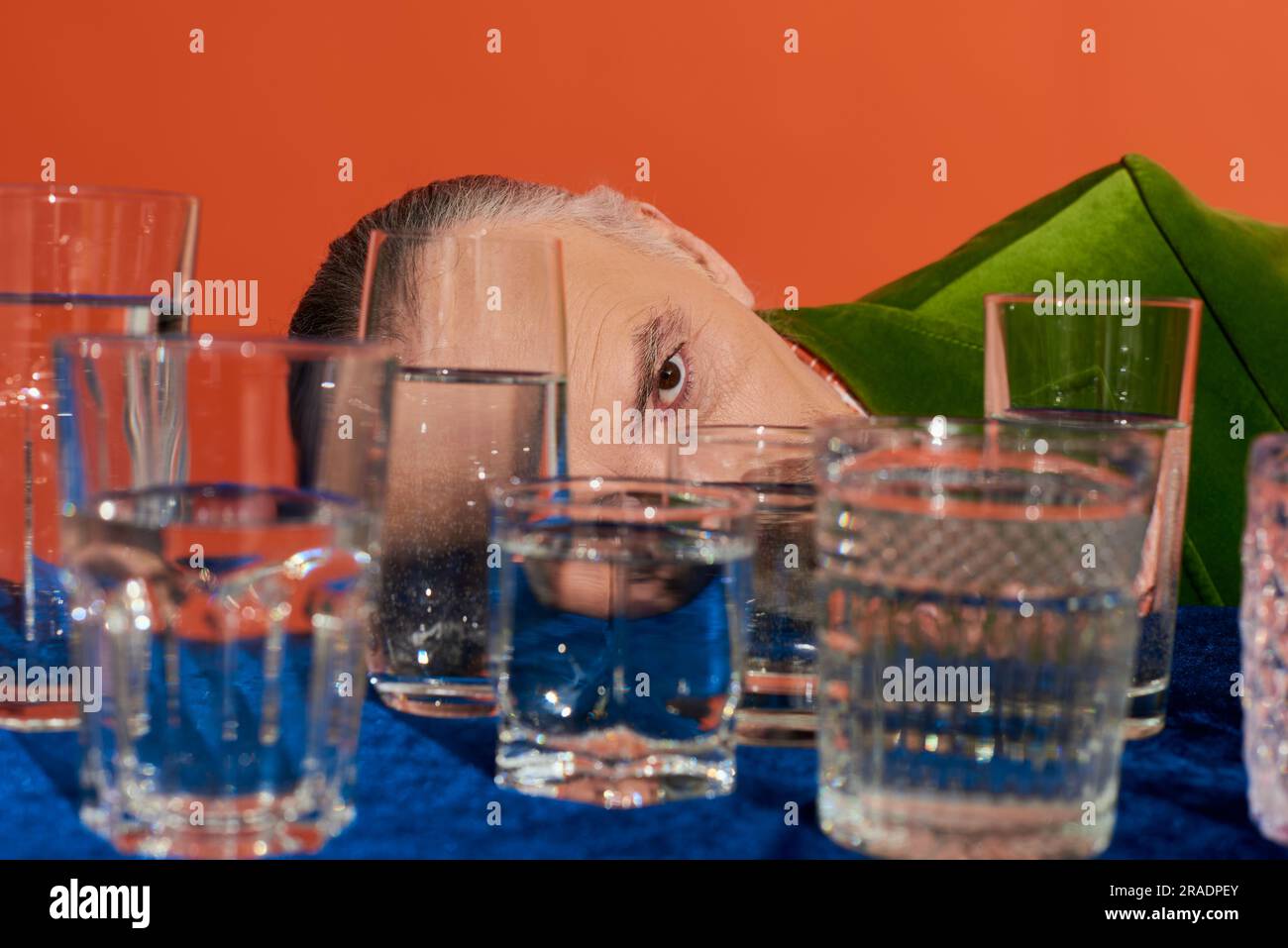 elderly man obscuring face behind transparent glasses with clear water ...