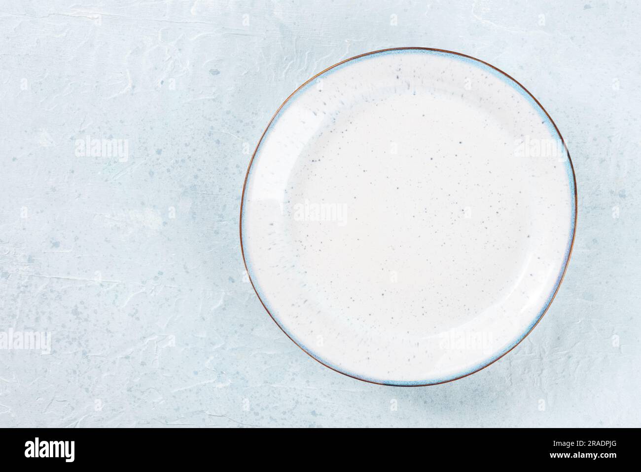 An empty white plate with a blue rim, shot from above on a slate ...