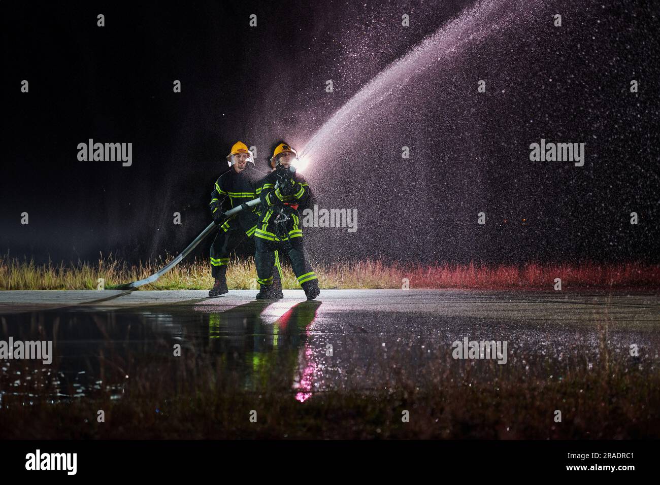 Firefighters using a water hose to eliminate a fire hazard. Team of ...