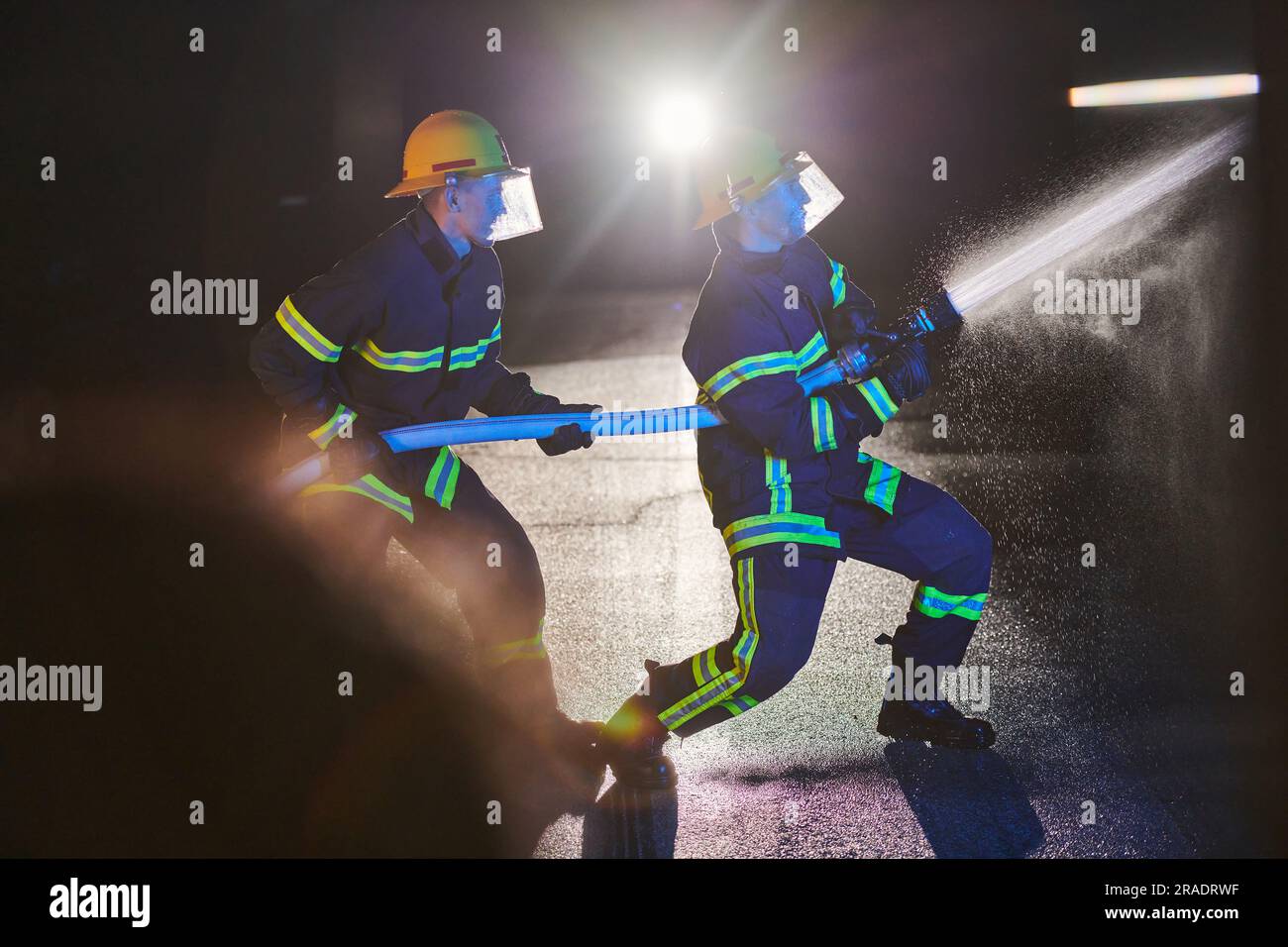 Firefighters using a water hose to eliminate a fire hazard. Team of ...