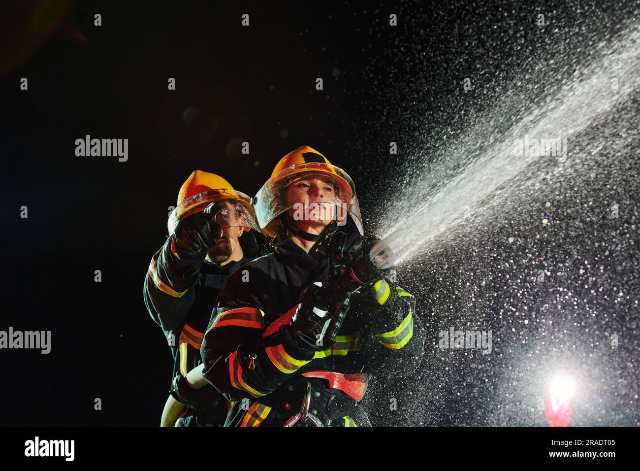 Firefighters using a water hose to eliminate a fire hazard. Team of ...