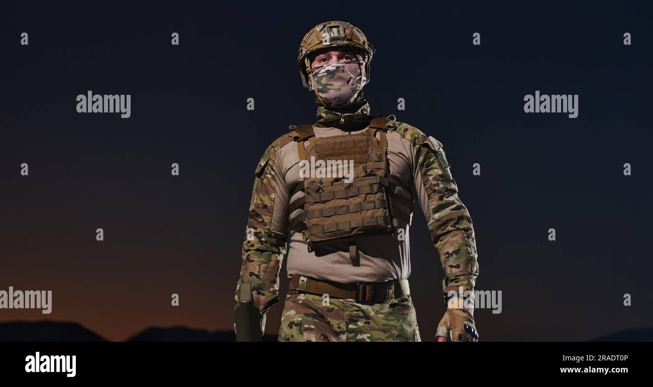 A professional soldier in full military gear striding through the dark ...
