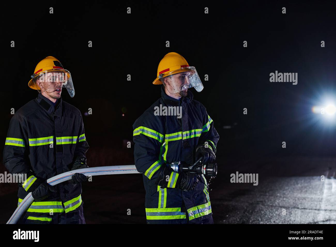 Firefighters using a water hose to eliminate a fire hazard. Team of ...