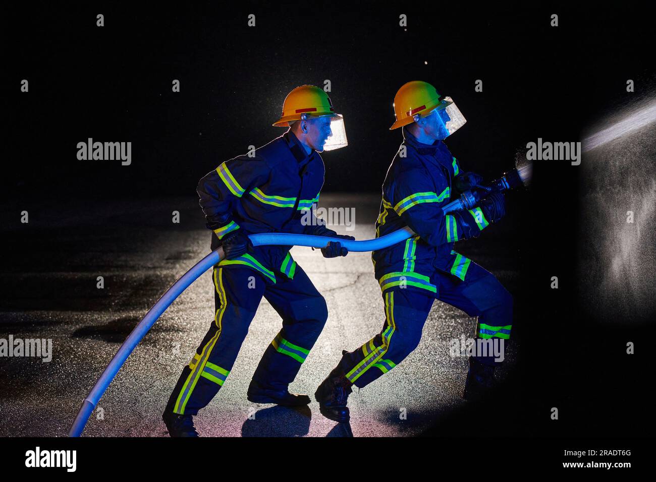 Firefighters using a water hose to eliminate a fire hazard. Team of ...