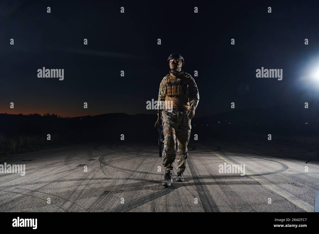 A professional soldier in full military gear striding through the dark ...