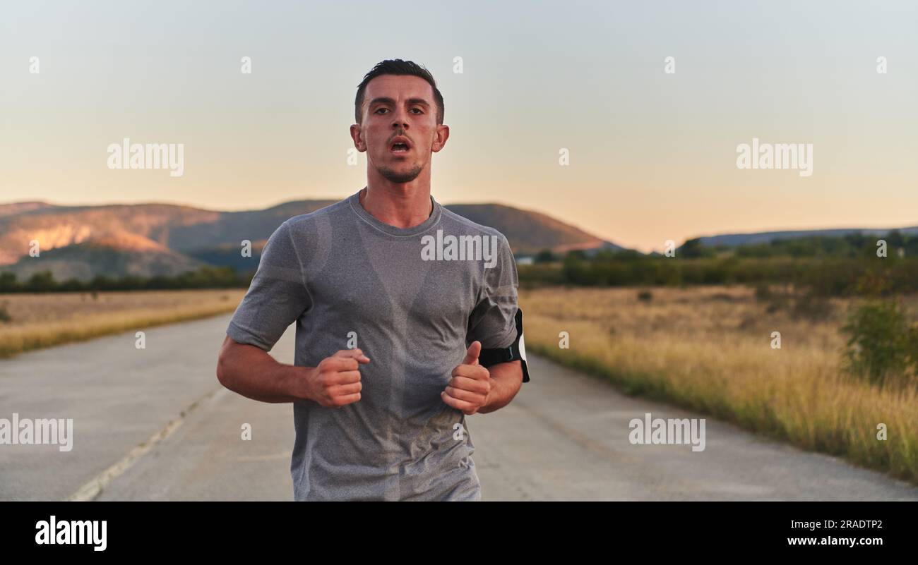 A young handsome man running in the early morning hours, driven by his ...