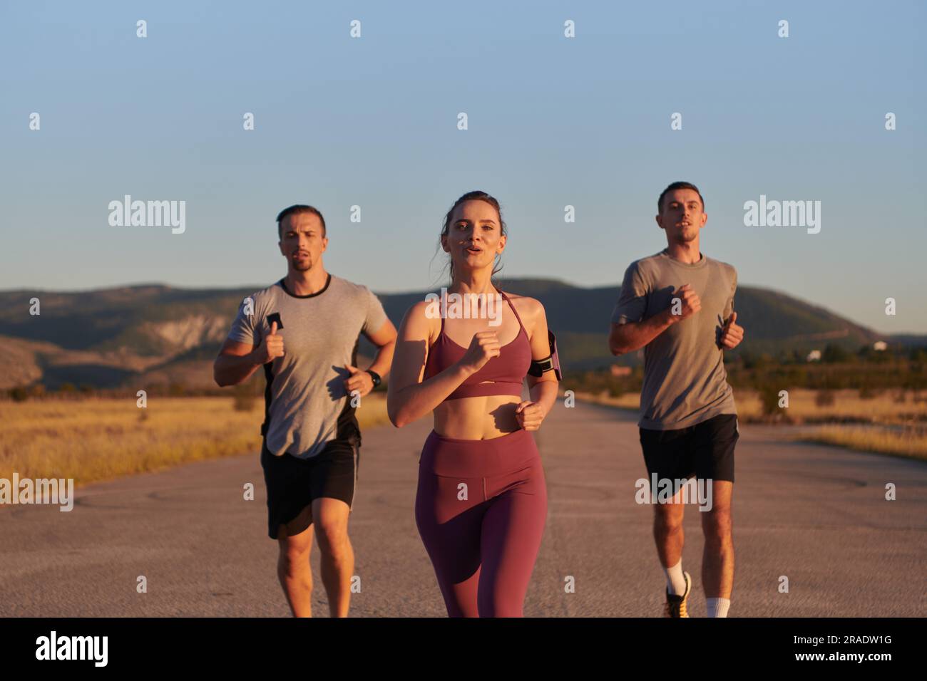A group of young athletes running together in the early morning light ...