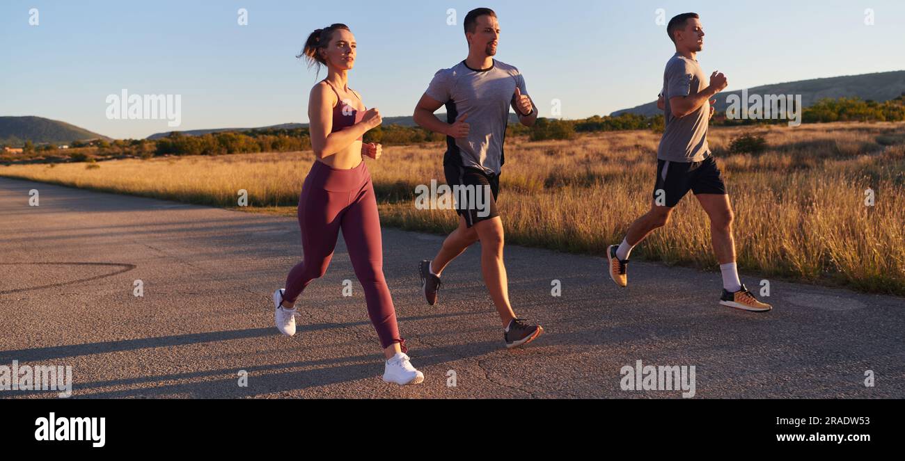 A group of young athletes running together in the early morning light ...