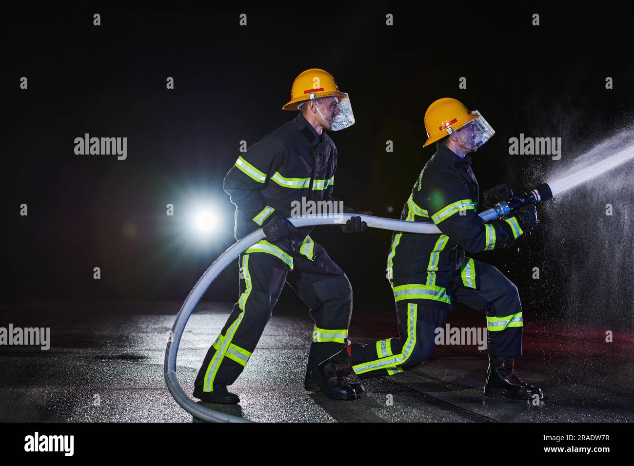 Firefighters using a water hose to eliminate a fire hazard. Team of ...