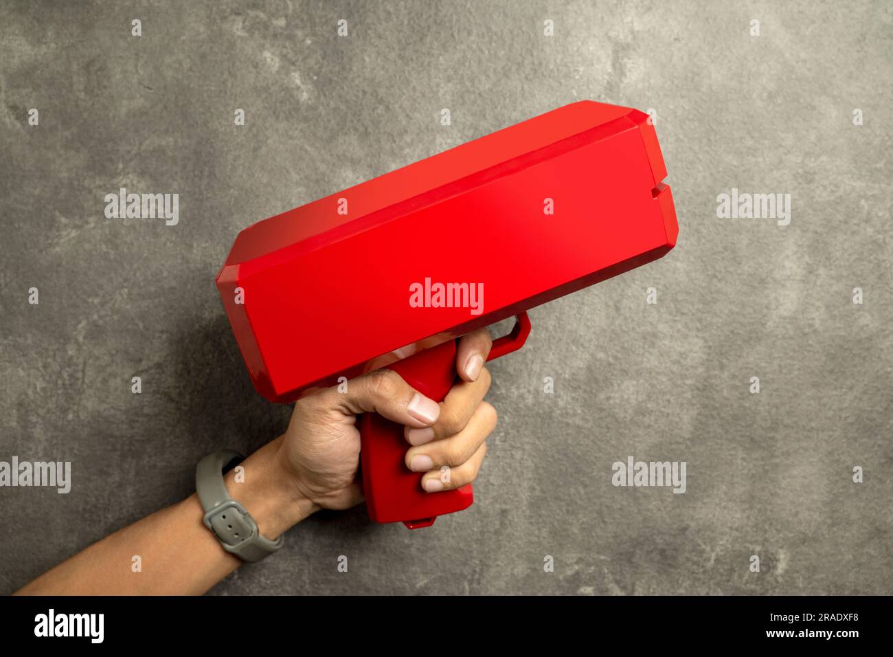A human hand holding a red money gun on black background Stock Photo ...