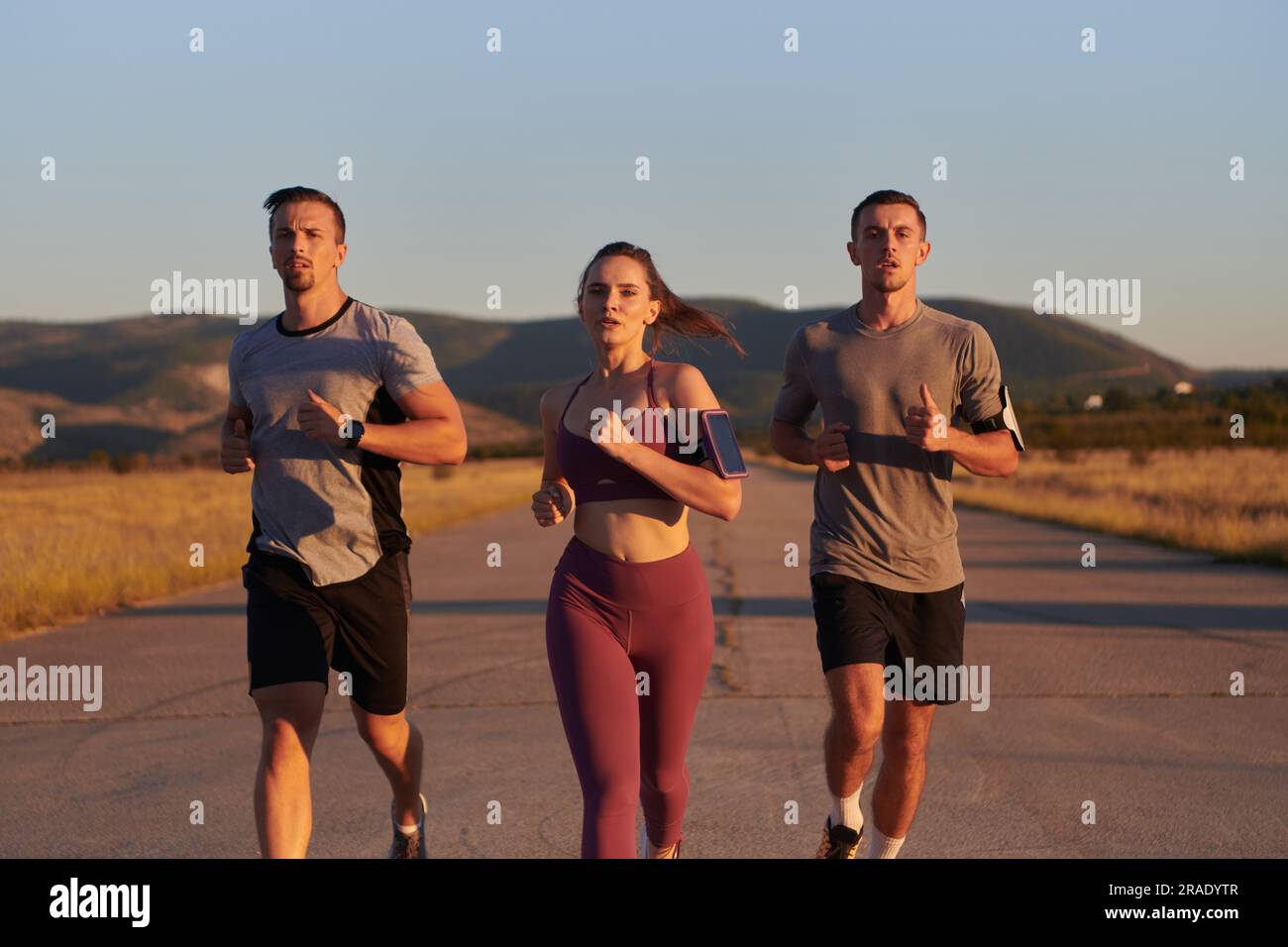 A group of young athletes running together in the early morning light ...