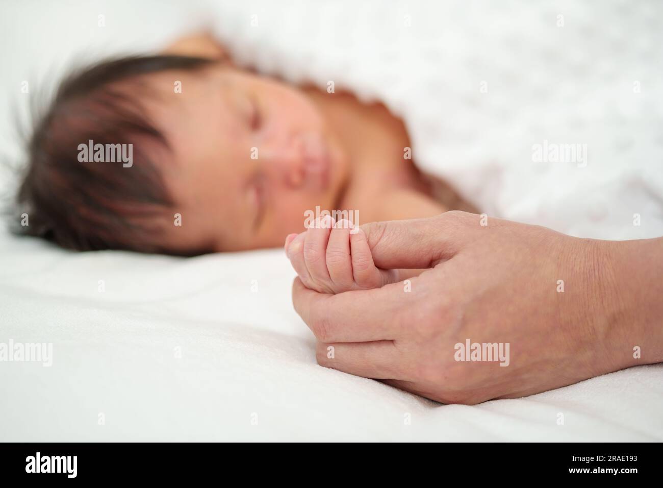 mother holding hand of sleeping newborn baby on a bed Stock Photo - Alamy