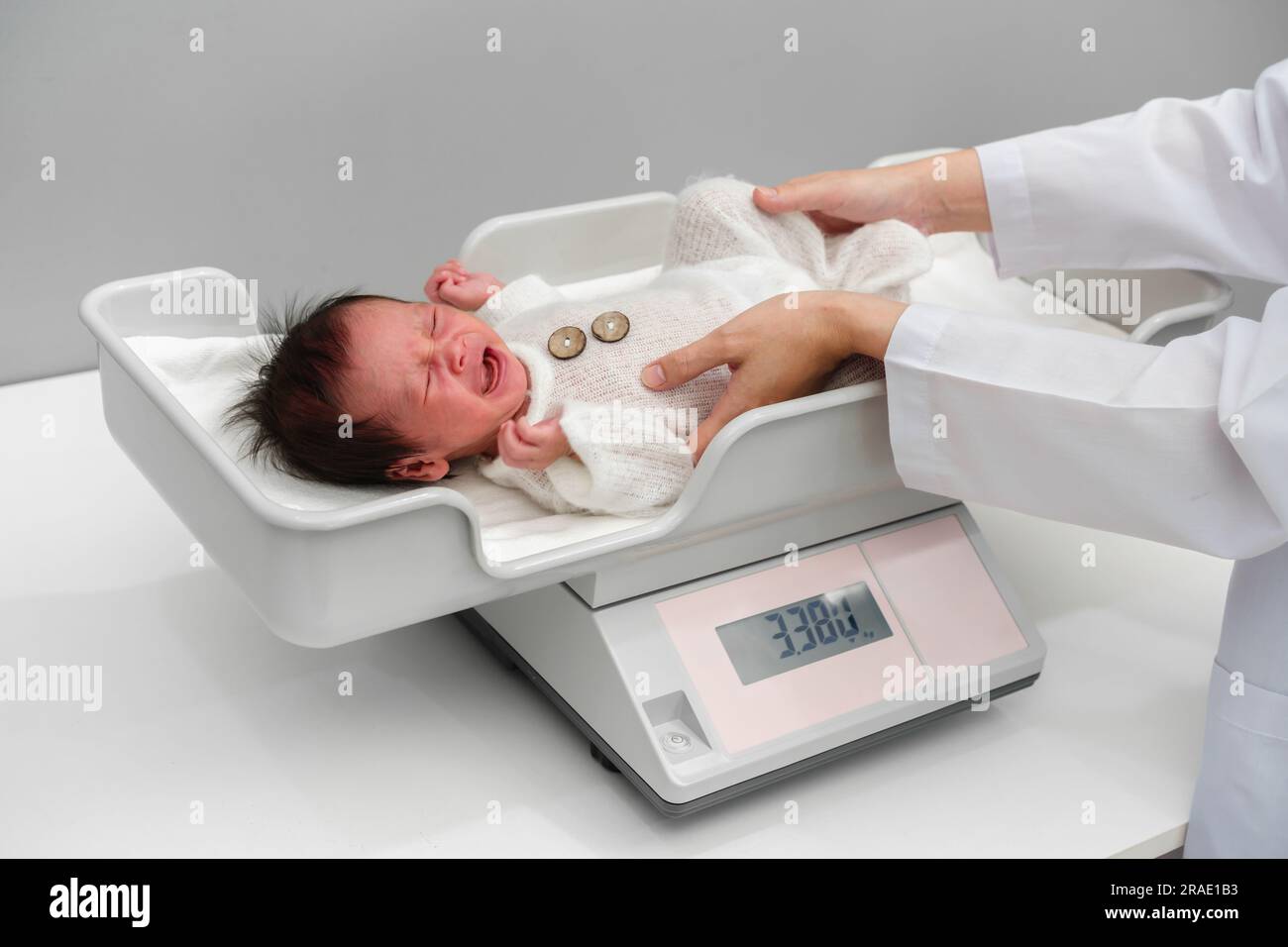 crying newborn baby weight measurement on the digital scales with ...