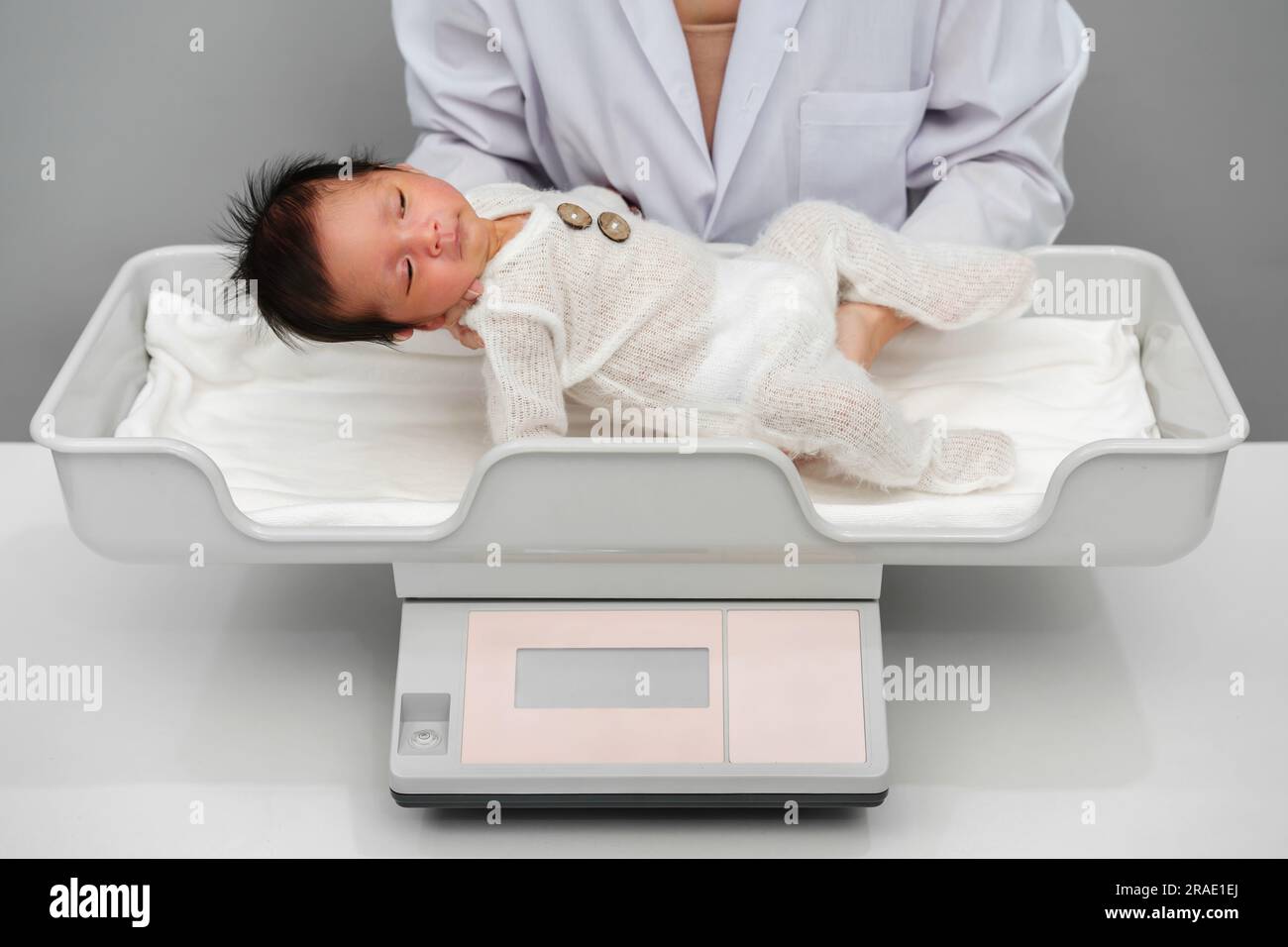 newborn baby weight measurement on the digital scales with doctor in ...