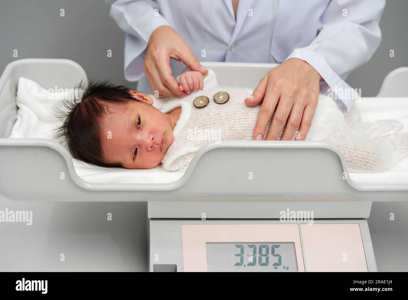 newborn baby weight measurement on the digital scales with doctor in ...