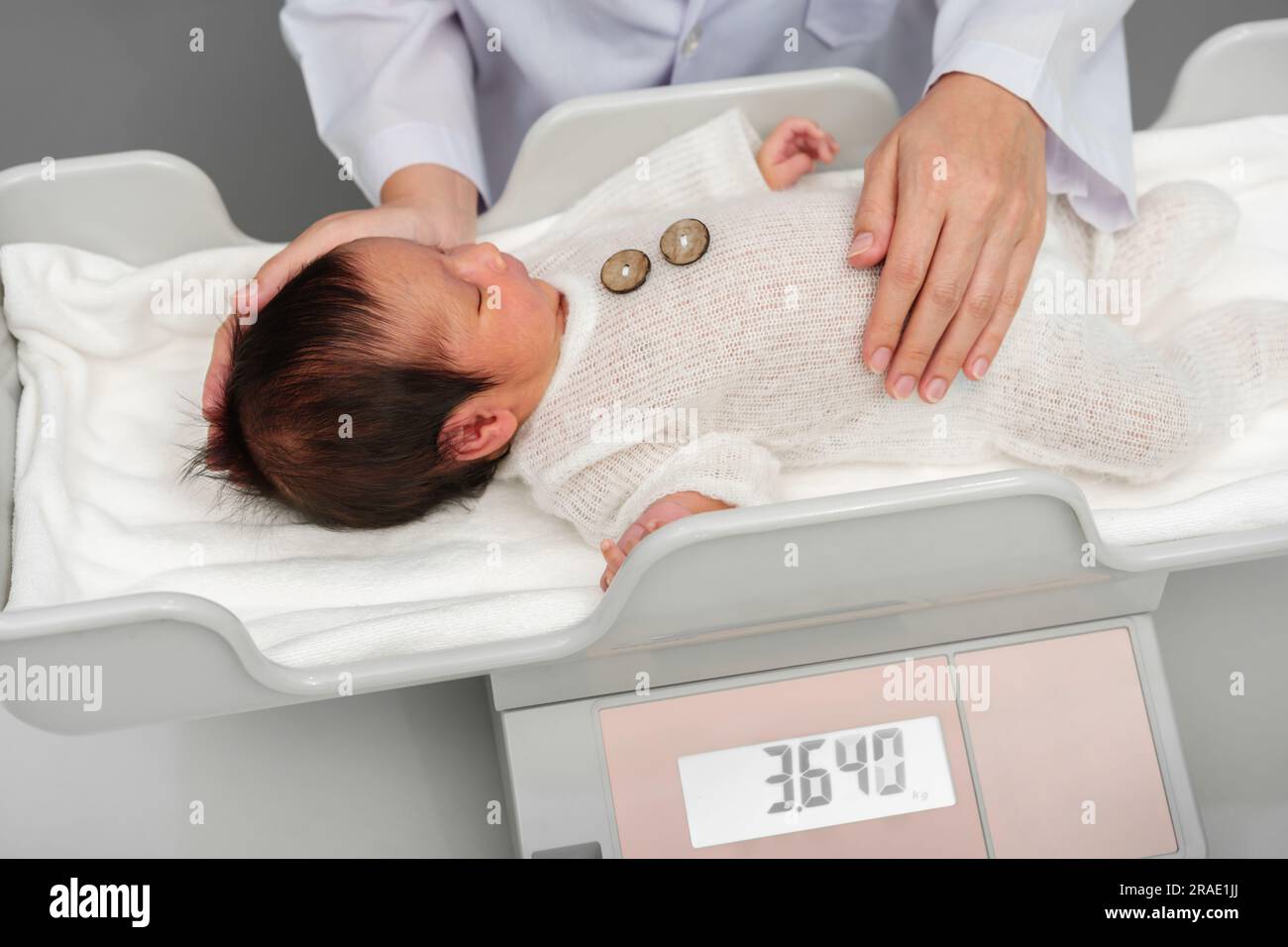 newborn baby weight measurement on the digital scales with doctor in ...
