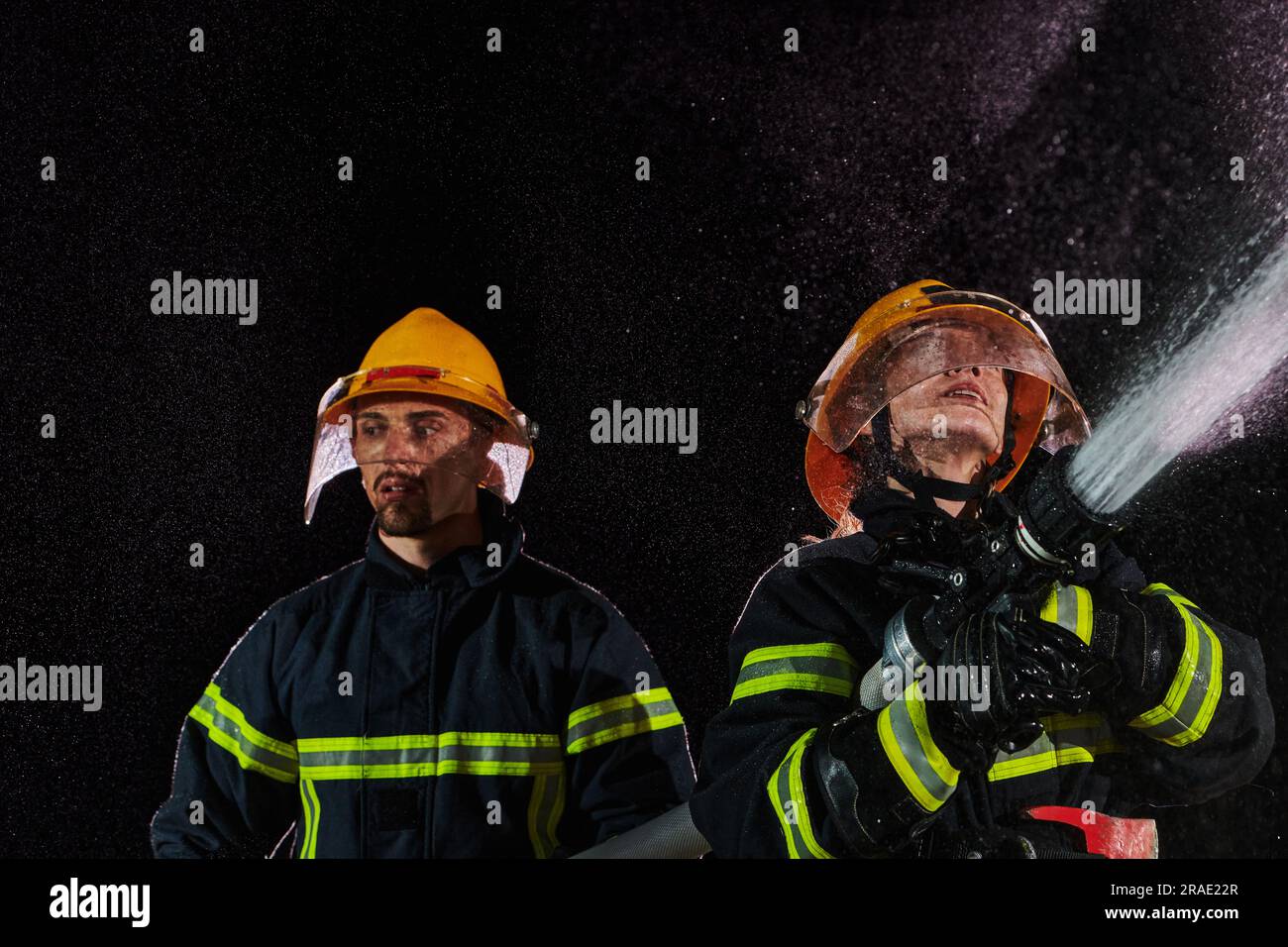 Firefighters using a water hose to eliminate a fire hazard. Team of ...