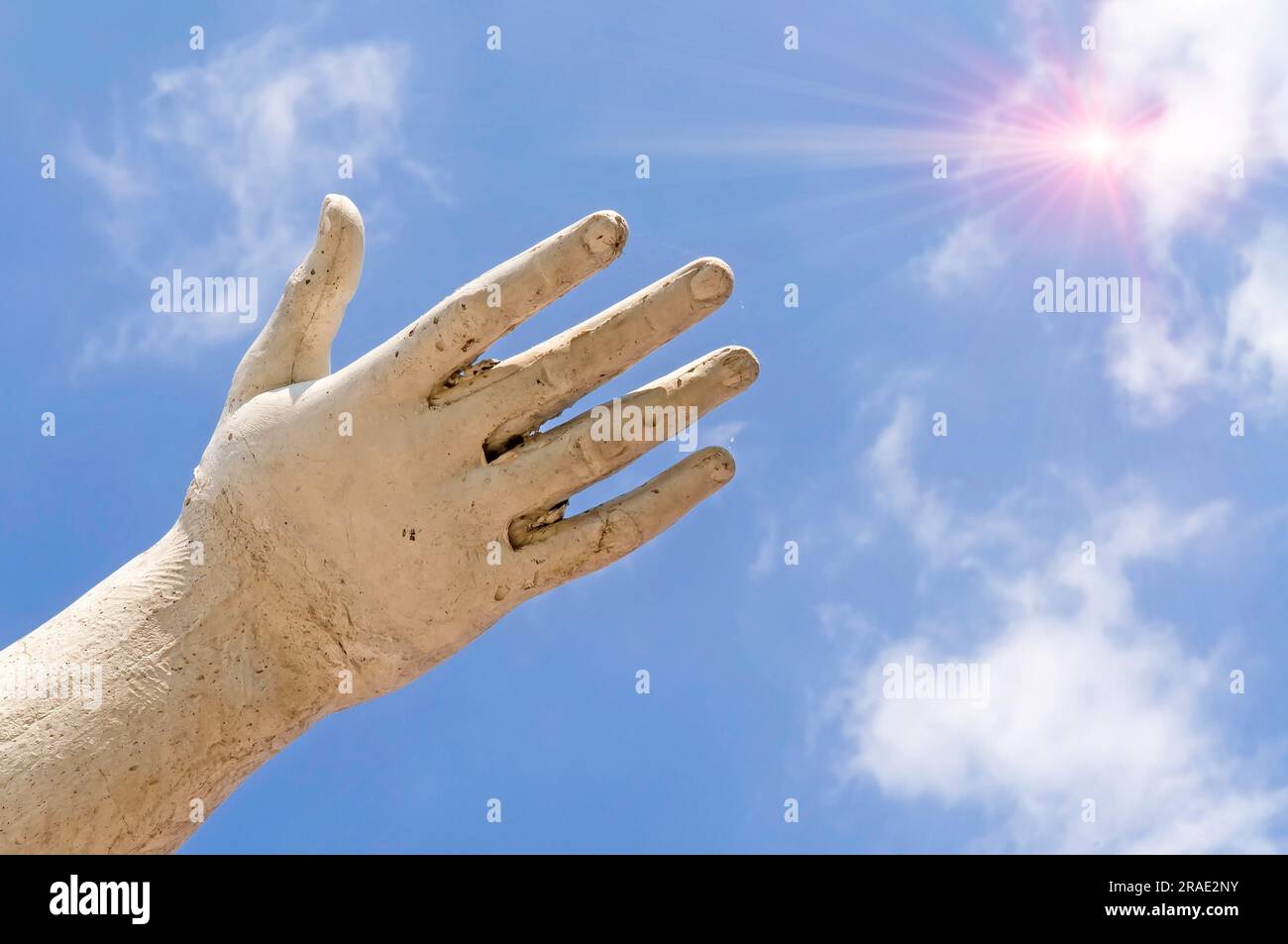 A statue hand showing the sun in the cloudy blue sky, as idea of ...