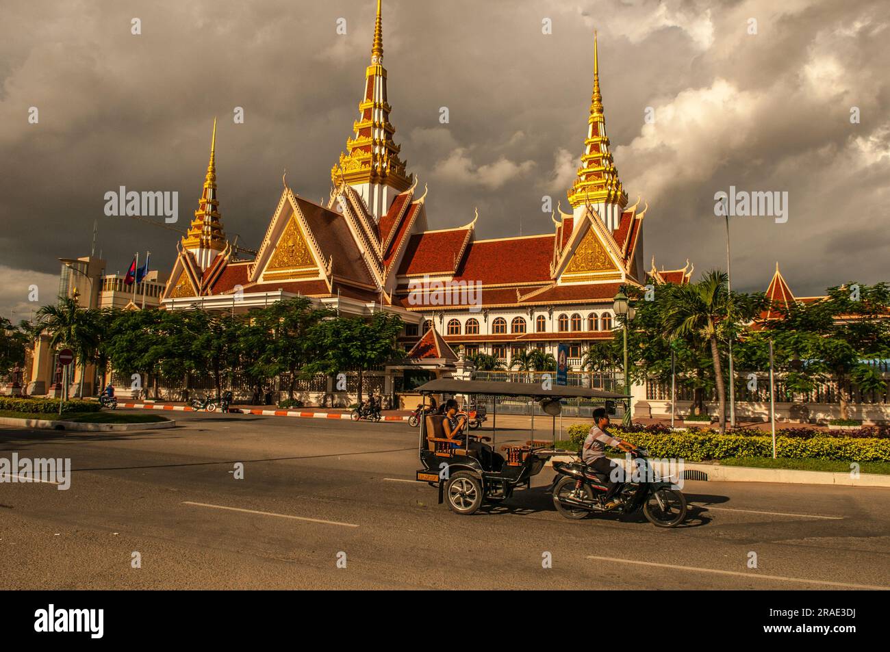 A tuk-tuk w/ a passenger passes The National Assembly Building during ...