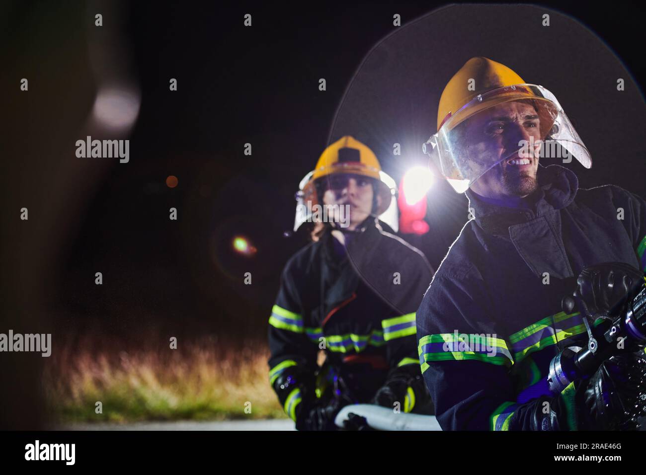 Firefighters using a water hose to eliminate a fire hazard. Team of ...