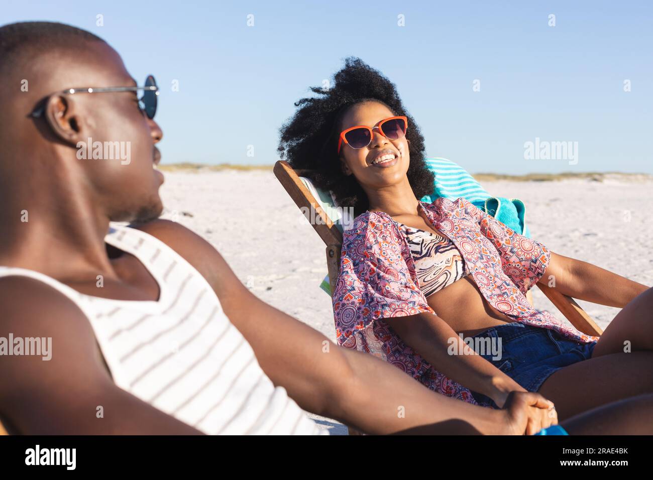 Happy African American Couple Sitting In Deckchairs Holding Hands On