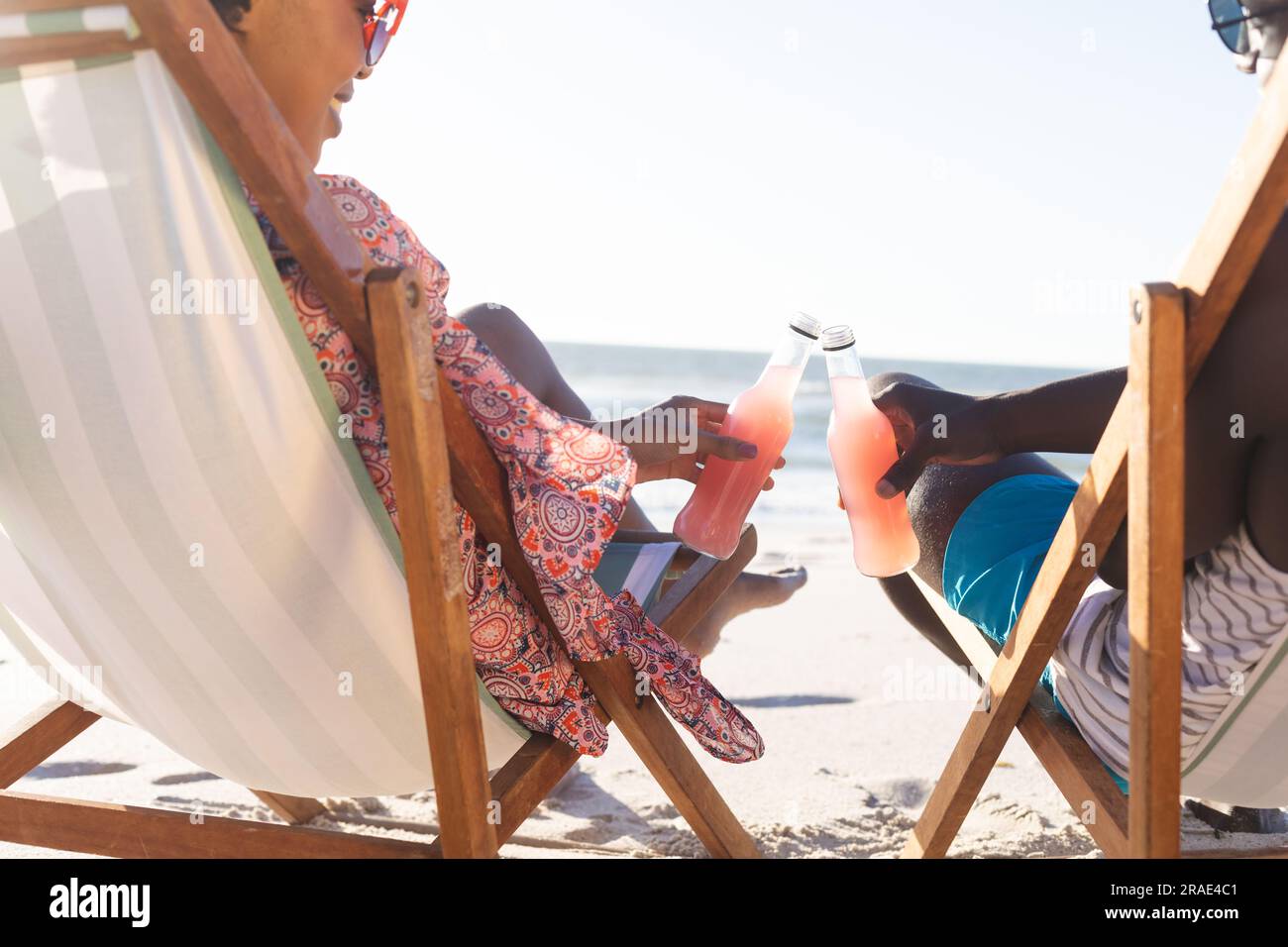 Happy African American Couple Sitting In Deckchairs Making A Toast With