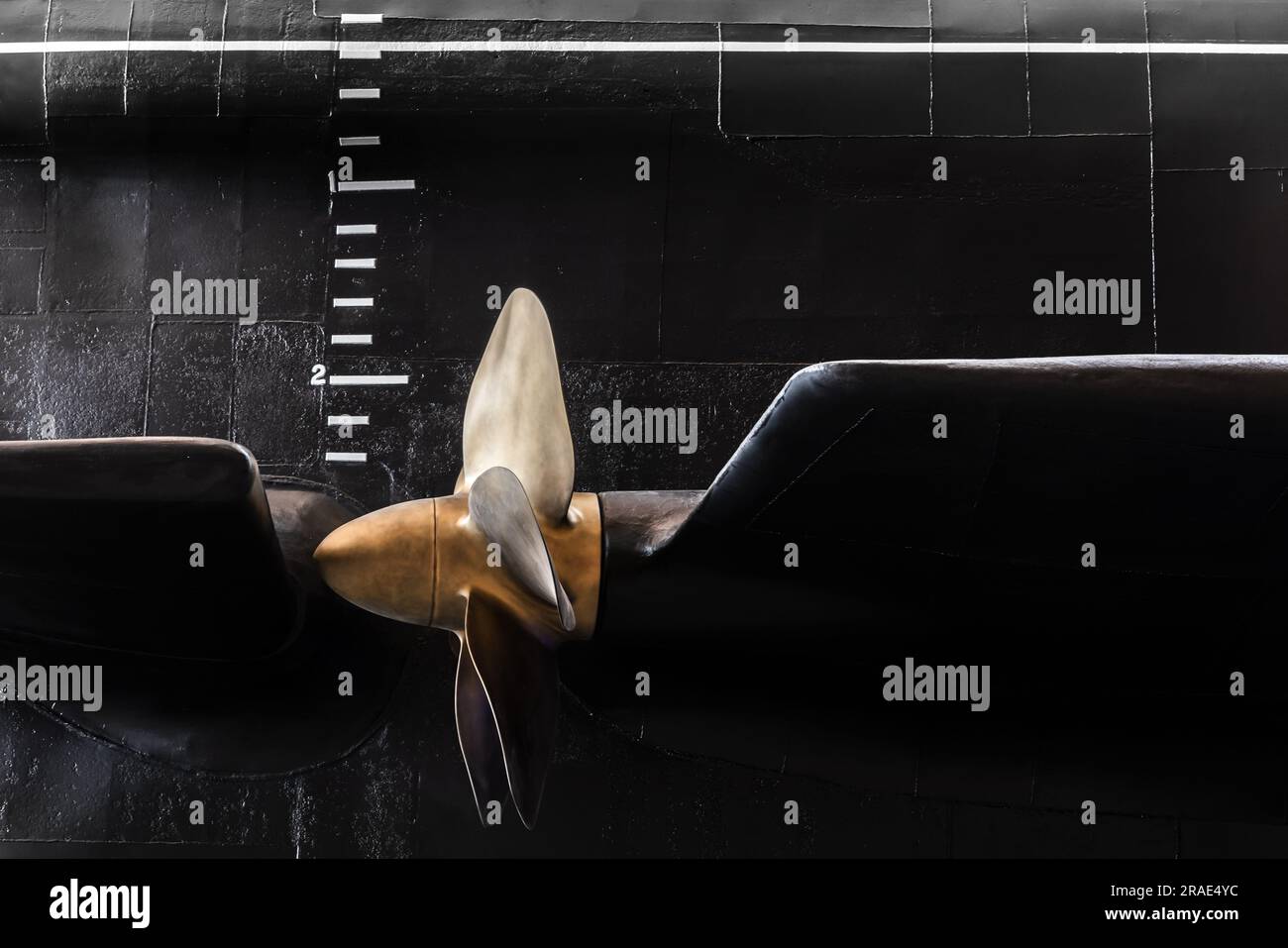 Huge shiny submarine propeller and draft scale on black hull, close up ...