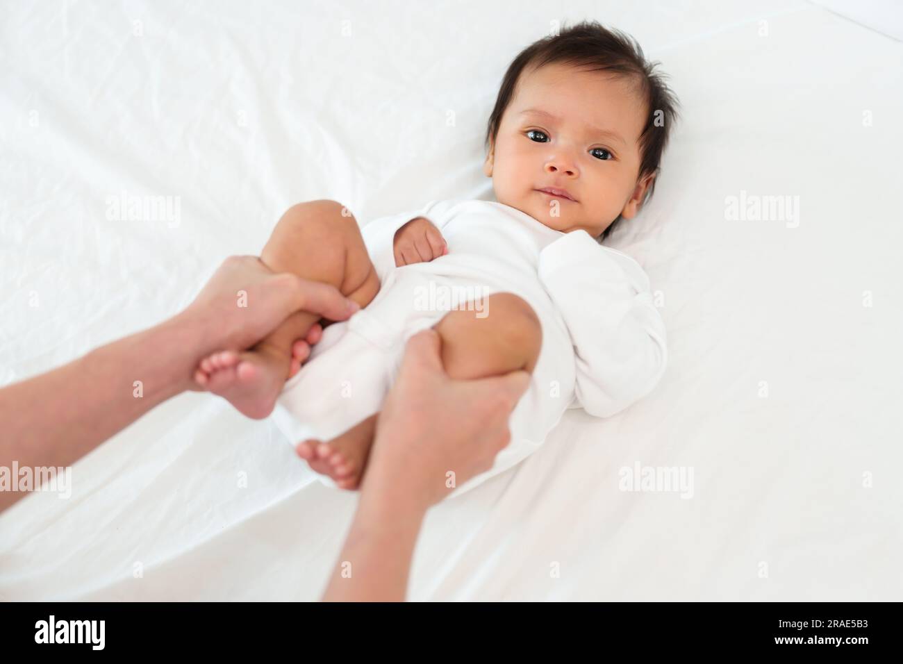 mother's hands holding baby legs and doing some playful exercises on a ...