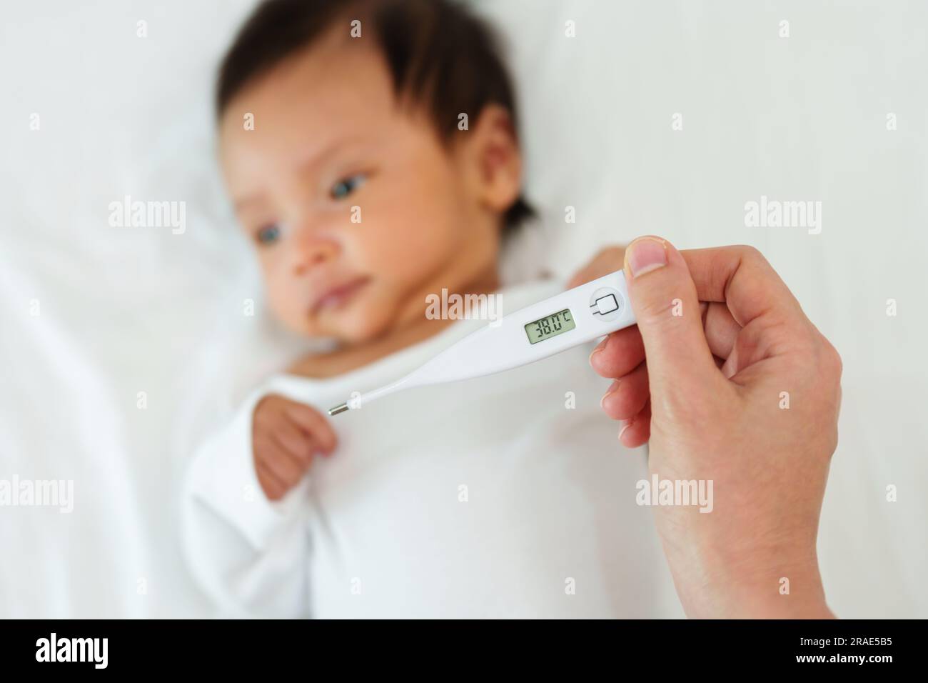 mother measuring temperature of her ill baby. sick child with high fever on a bed Stock Photo ...
