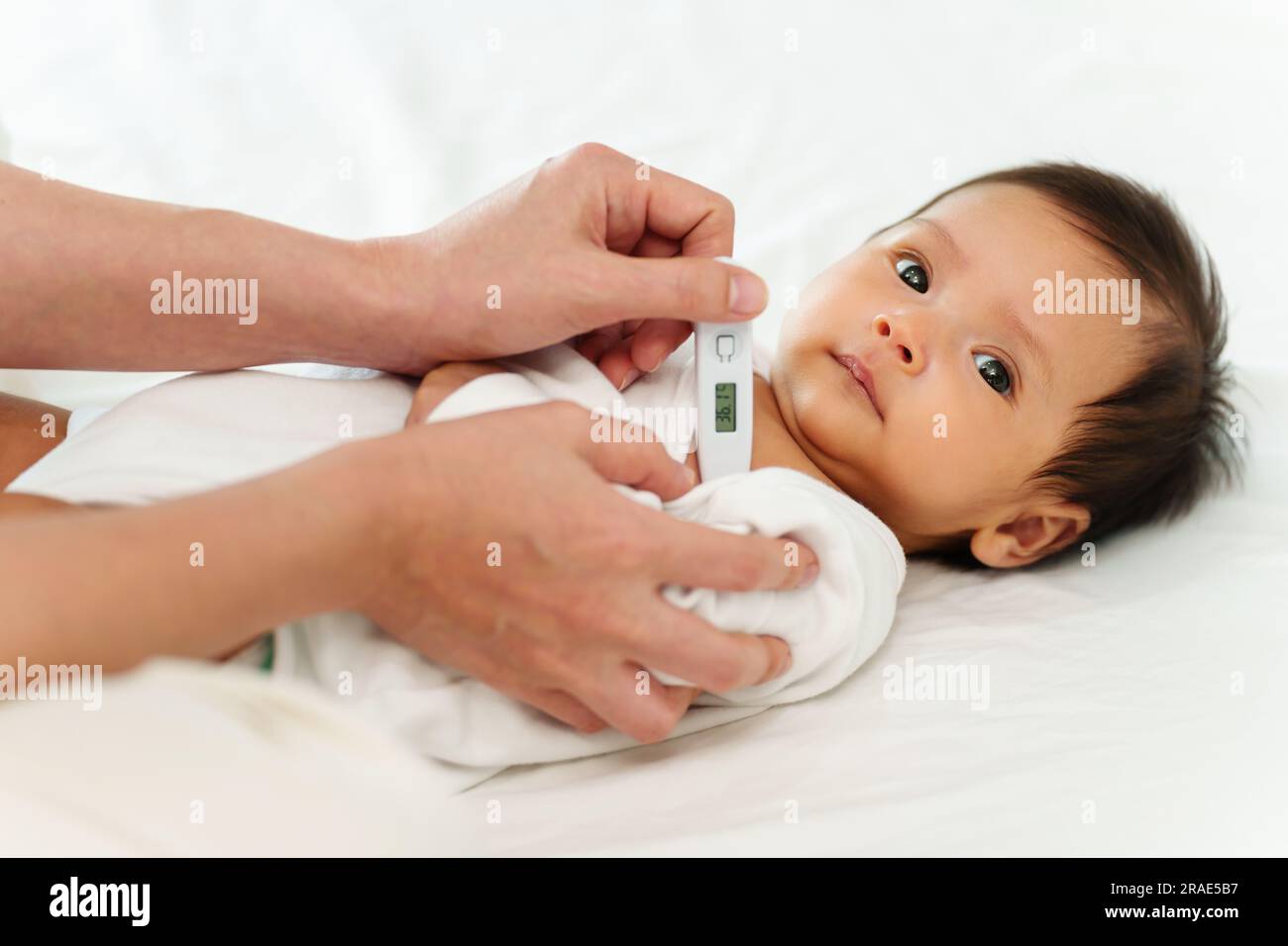 mother measuring temperature at armpit of ill baby. sick child with ...
